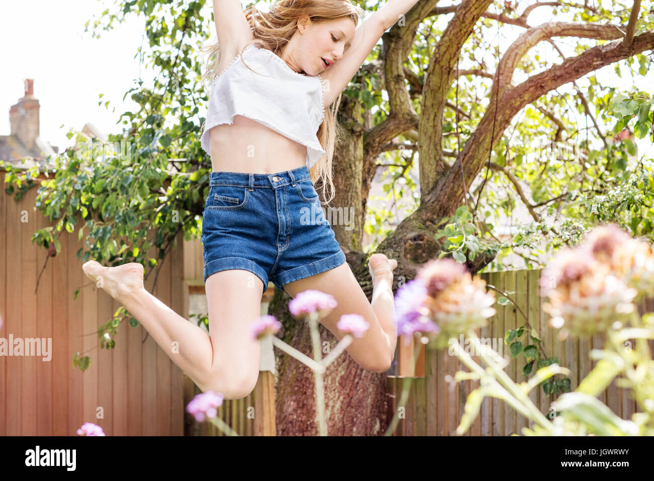 Teenage girl in garden jumping in air Stock Photo - Alamy