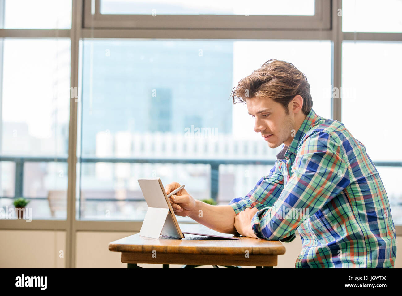 Young male digital designer at office table using laptop Stock Photo ...