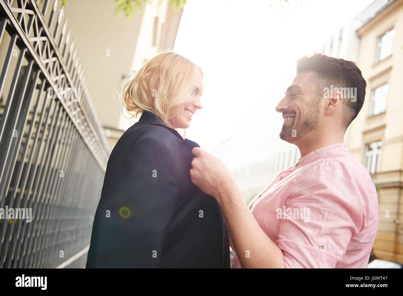Man in street sharing suit jacket with woman Stock Photo - Alamy