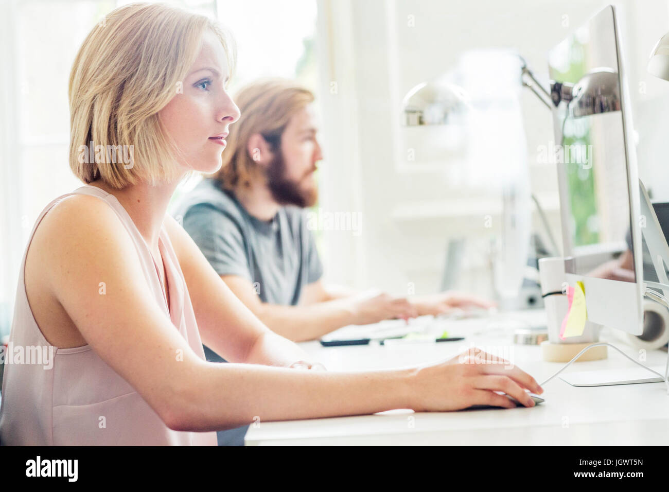 Male and female designers using desktop computers in creative studio ...
