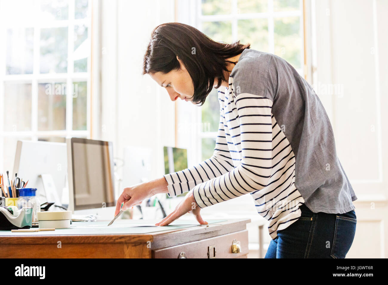 Female designer cutting paper with scalpel in creative studio Stock ...