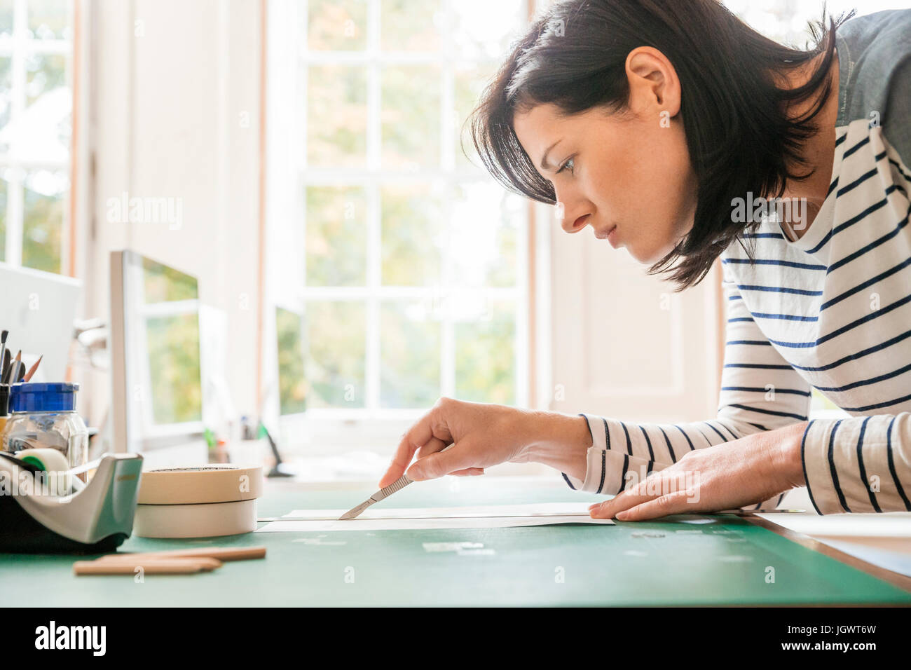 Female designer cutting paper with scalpel in creative studio Stock ...