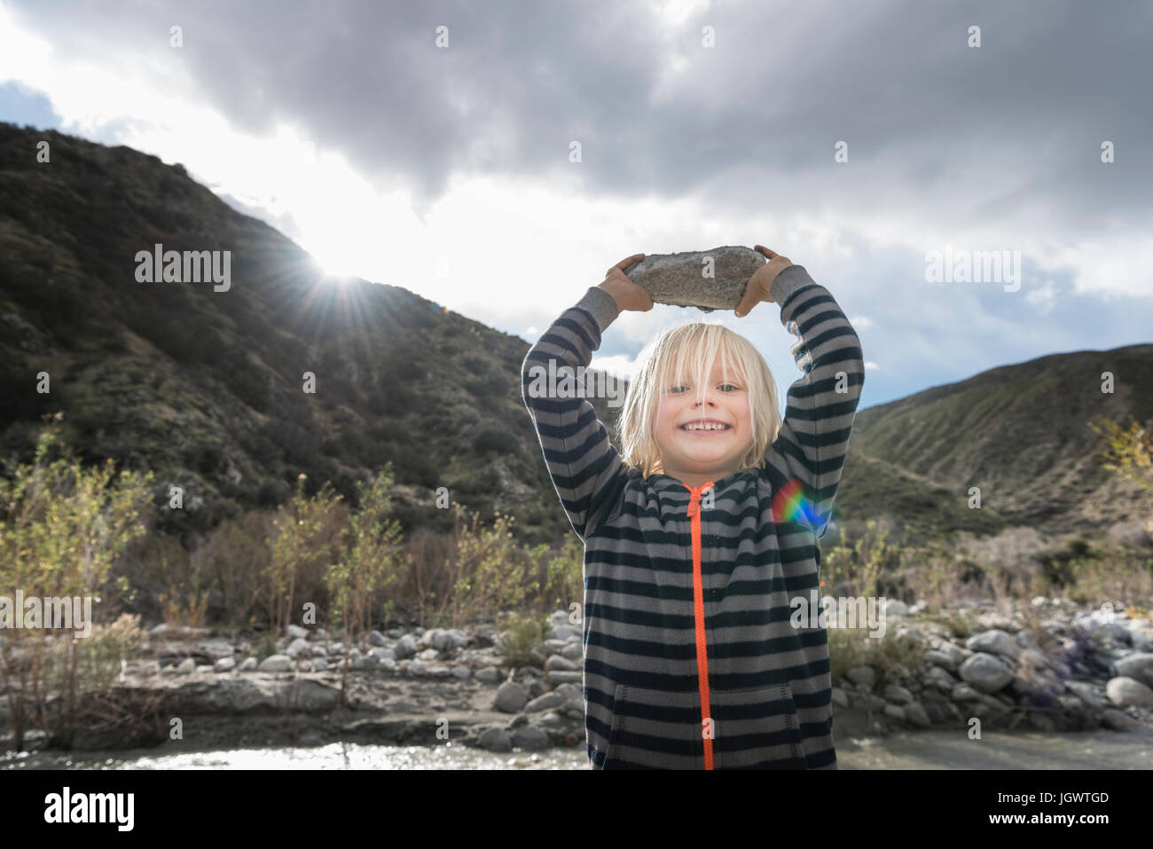 Portrait of cute boy holding up rock from riverbed Stock Photo - Alamy