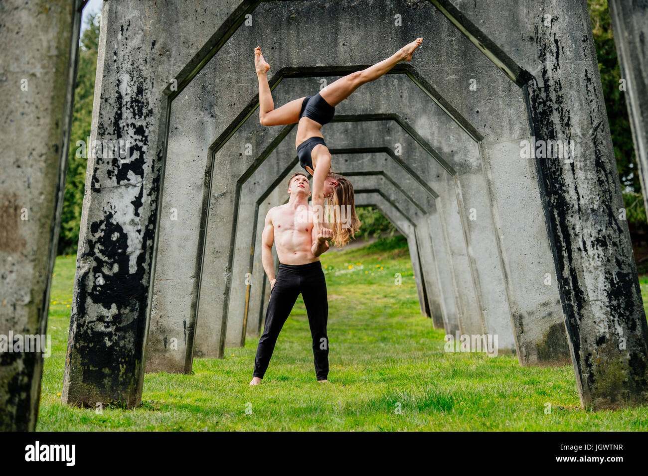 Young woman balancing on top of man hands, practicing yoga below ...