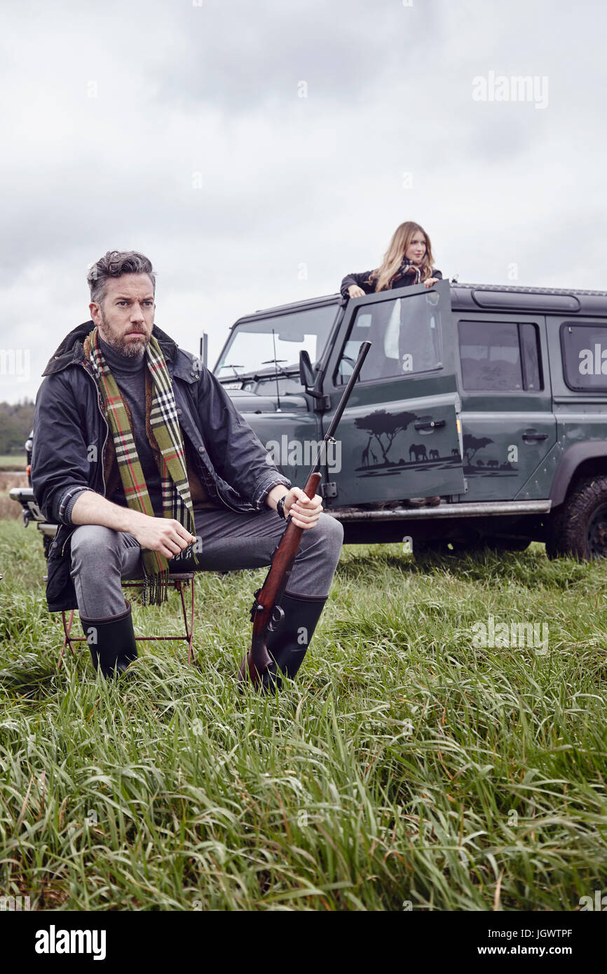 Man hunting, sitting in field with shot gun Stock Photo - Alamy