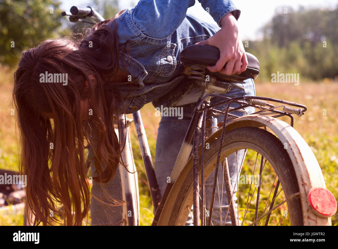 Teenage girl leaning over her bicycle in field Stock Photo - Alamy
