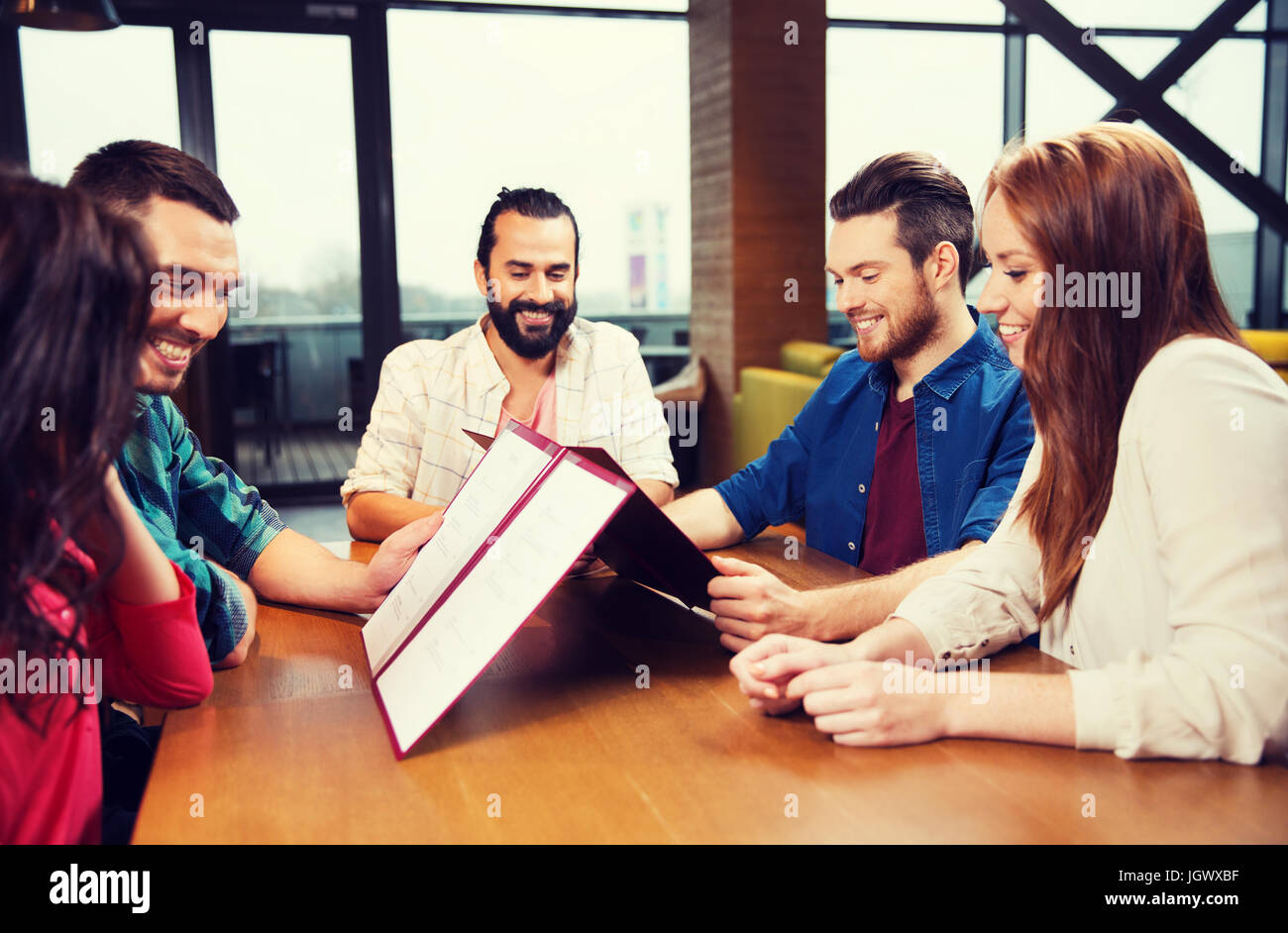 smiling friends discussing menu at restaurant Stock Photo - Alamy