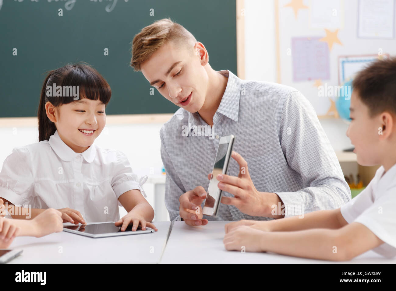 Male teacher helping students study in classroom Stock Photo - Alamy