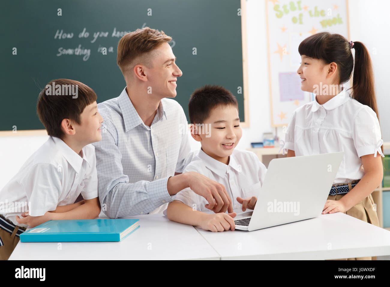Male teacher helping students study in classroom Stock Photo - Alamy