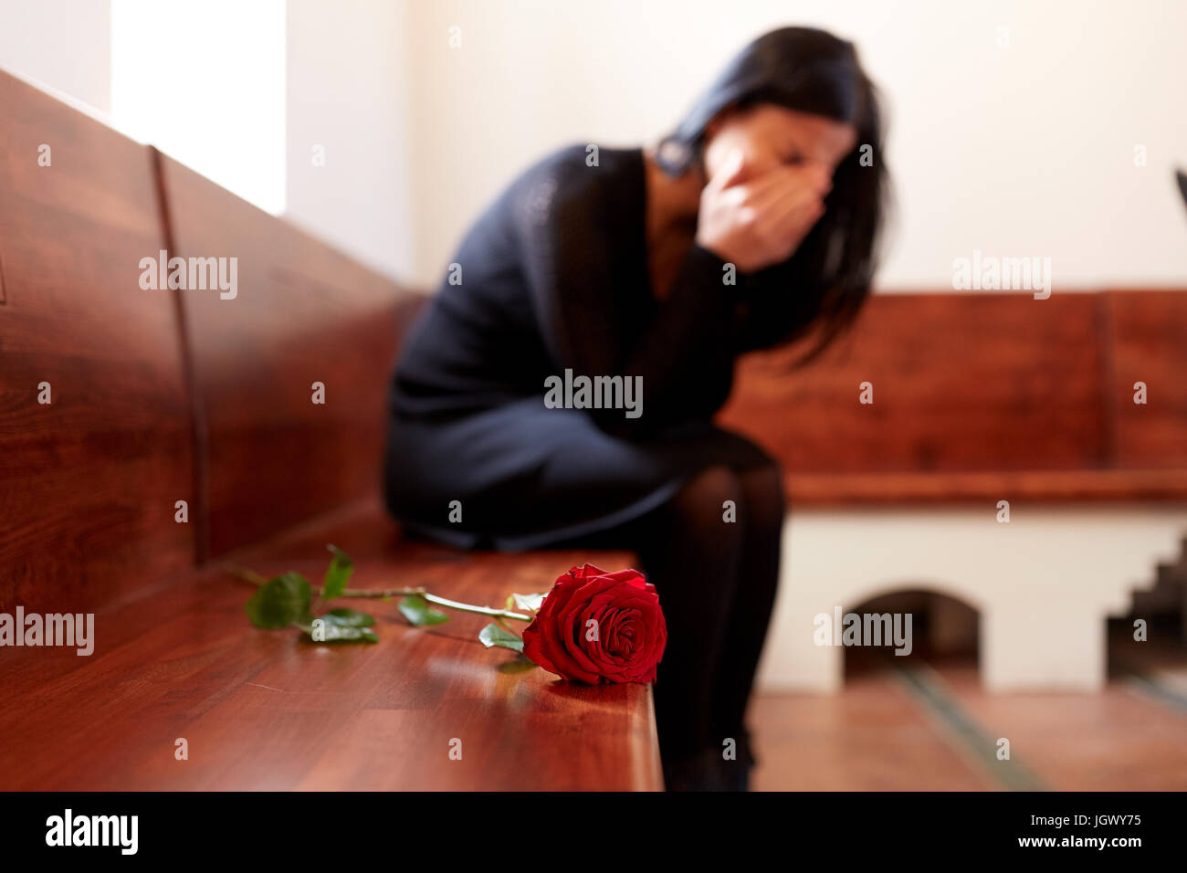 crying woman with red rose at funeral in church Stock Photo - Alamy