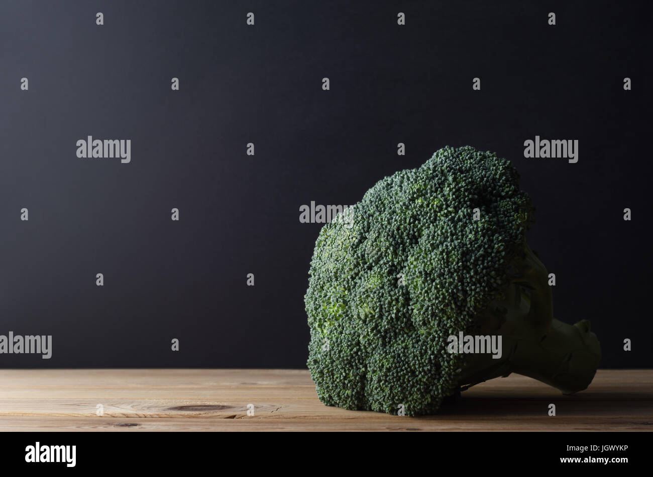 A head of dark green broccoli with stalk intact, on wooden planked ...