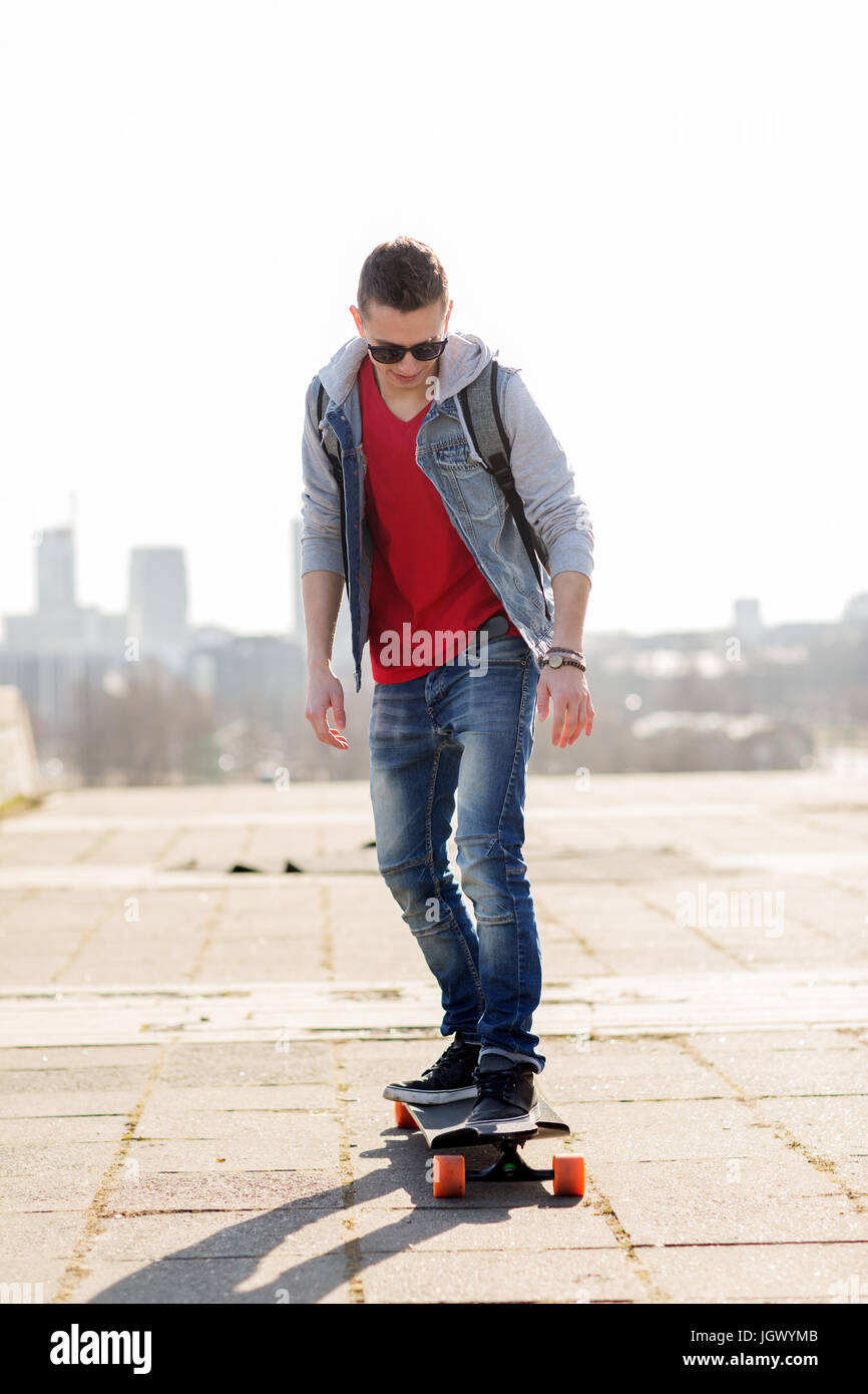 happy young man or teenage boy riding on longboard Stock Photo - Alamy