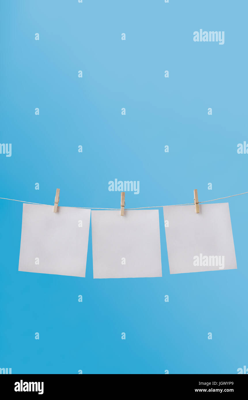 Vertical image of three squares of note paper for messages, pegged to ...