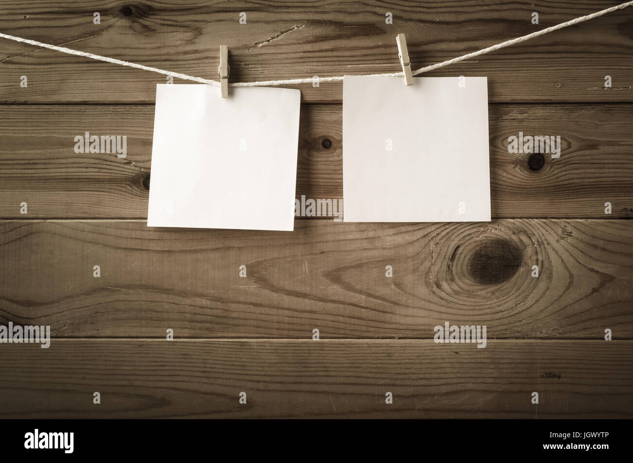 Two squares of blank paper, pegged to a string washing line, with wood ...