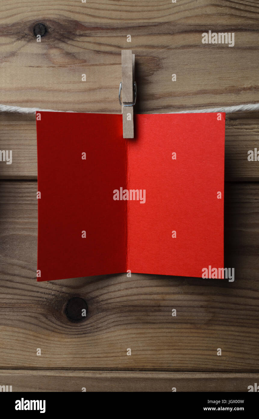 An opened, blank red greeting or Christmas card, pegged on to string ...