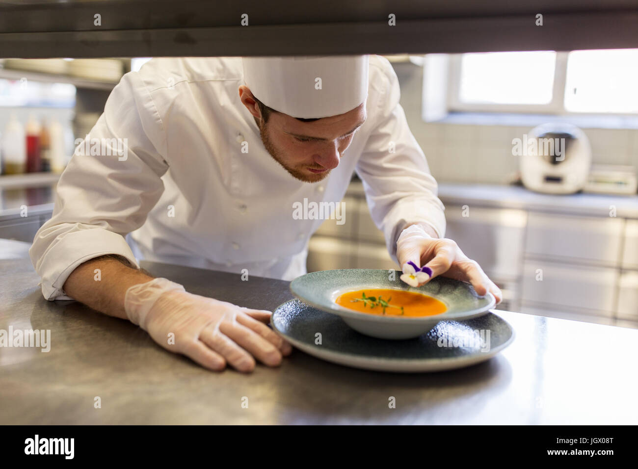male chef decorating dish with pansy flower Stock Photo - Alamy