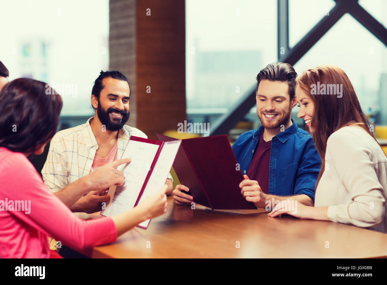 smiling friends discussing menu at restaurant Stock Photo - Alamy