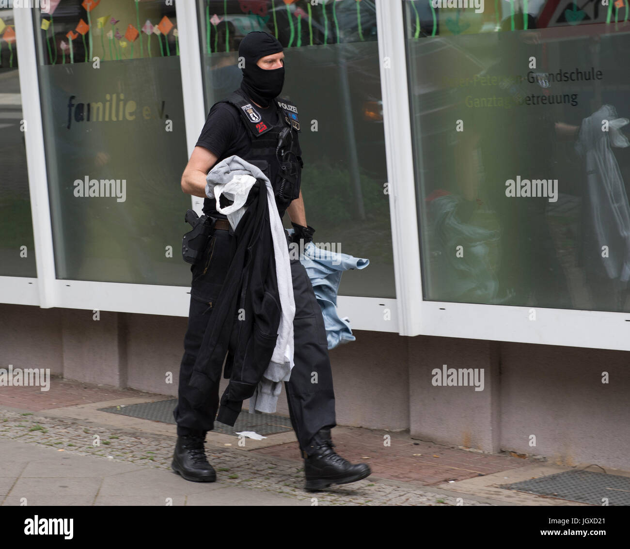 Berlin, Germany. 12th July, 2017. A masked police officer walks with ...