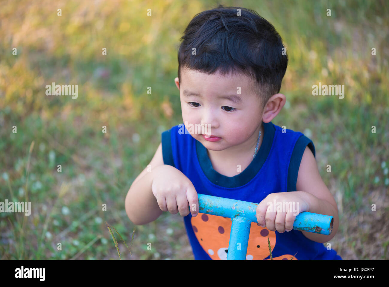 Sad kid play teeter-totter at the playground under sunlight, in ...