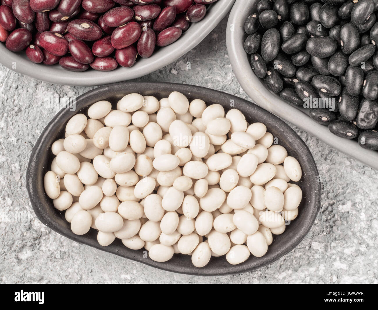 Top view of raw white beans in trendy plate on gray concrete background ...