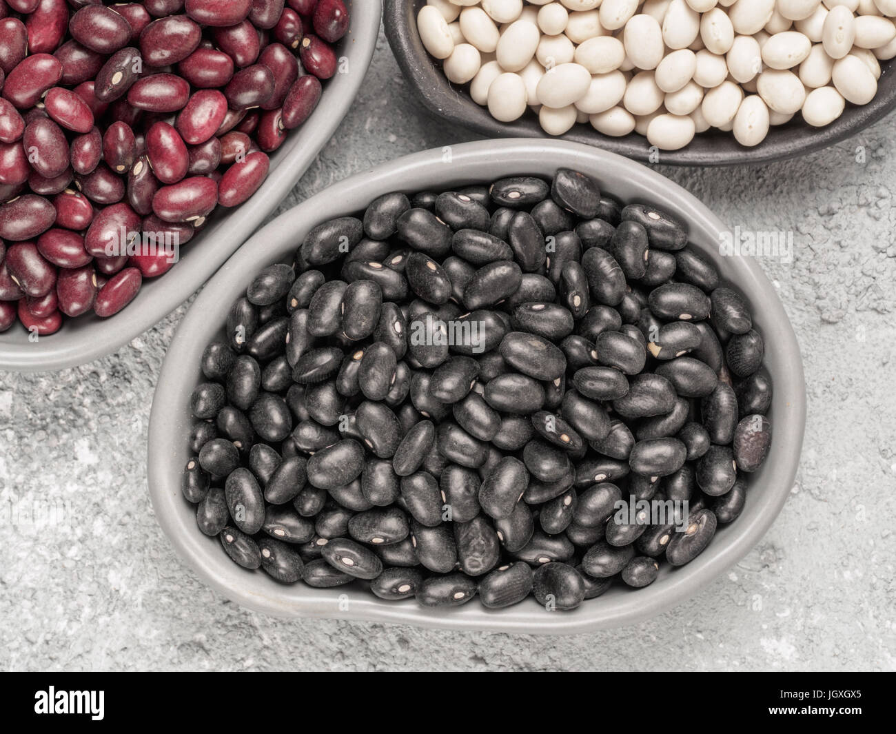Top view of raw black beans in trendy plate on gray concrete background ...