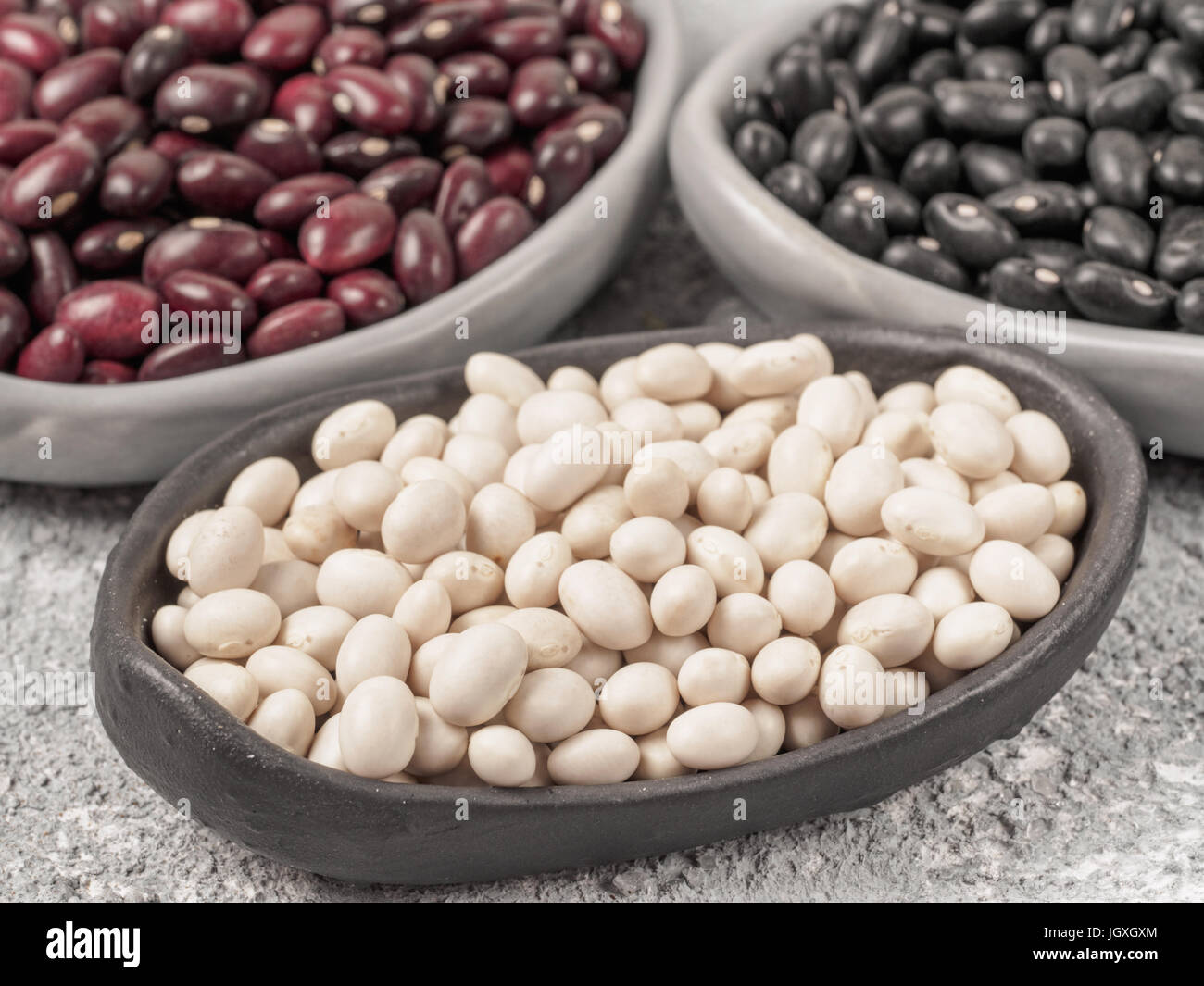 Close up view of raw white beans in trendy plate on gray concrete ...