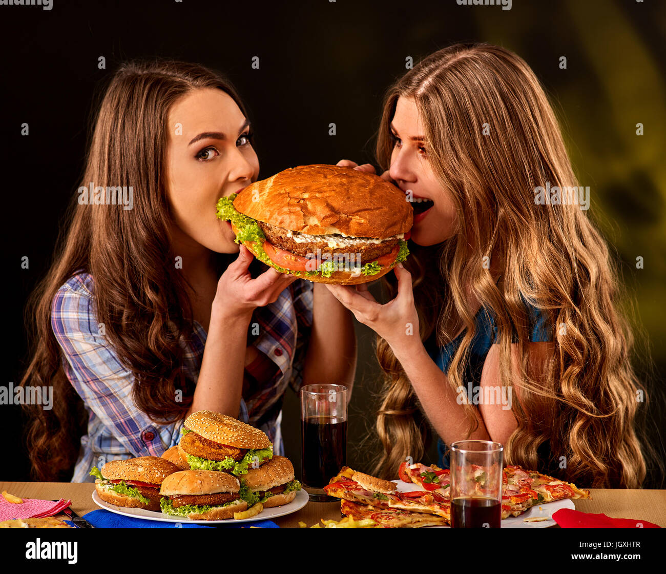 Women eating fast food. Gils eat hamburger with ham Stock Photo - Alamy