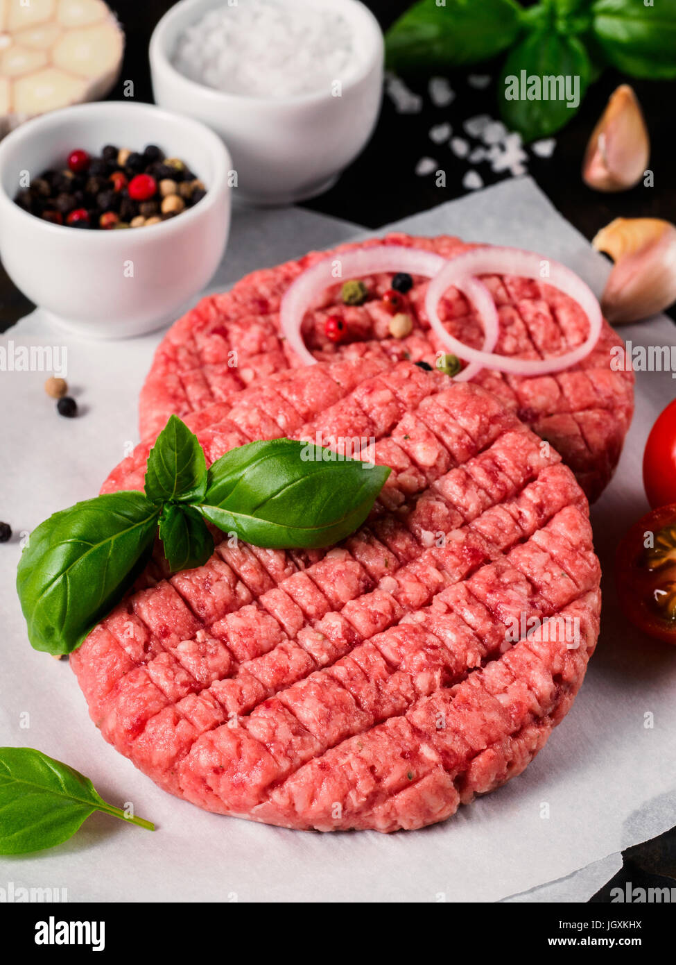 Close up view of two raw meat steak cutlets for burger with vegetables ...