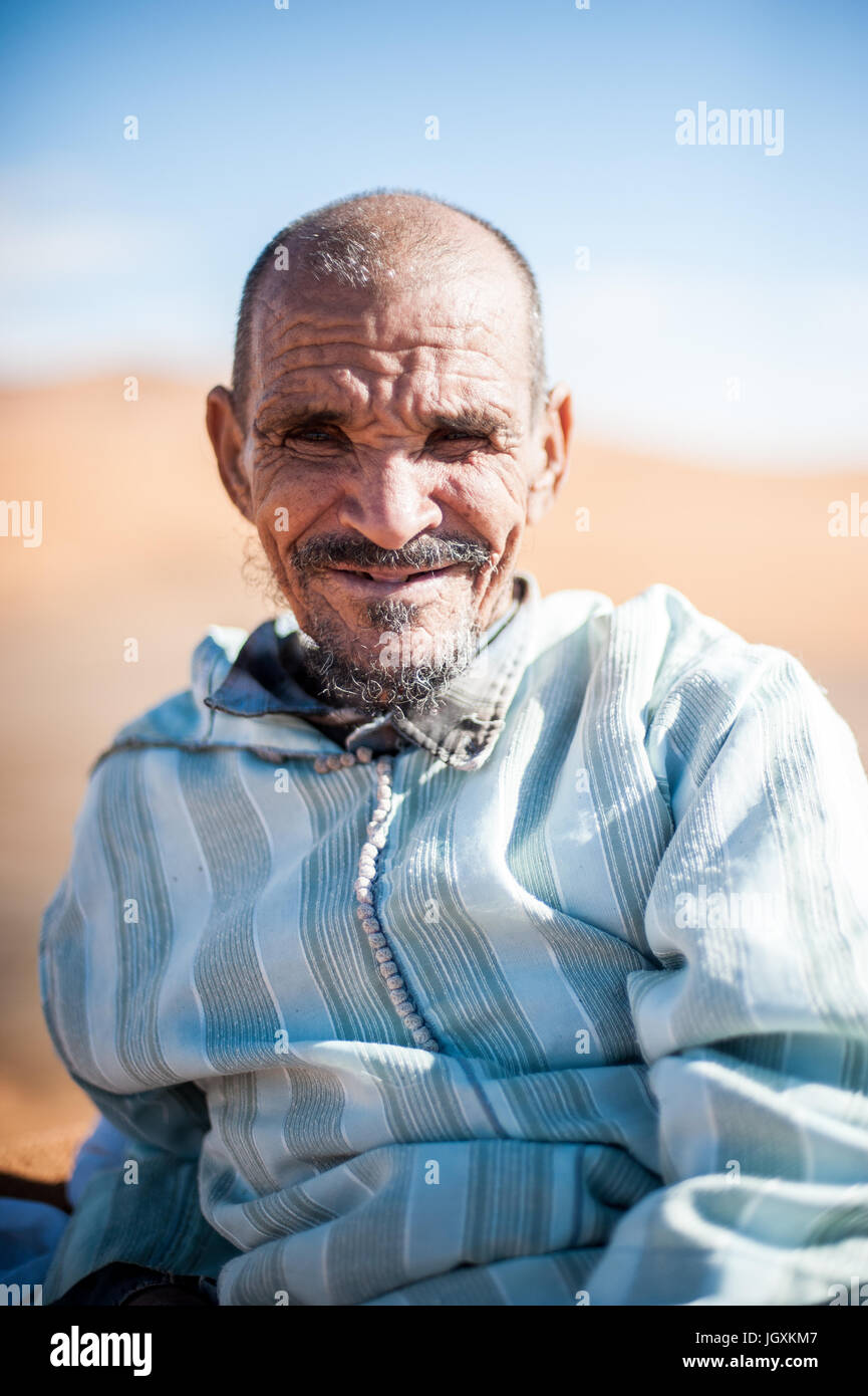 Portrait of old man who is resting on a dune erg chebbi at Merzouga ...