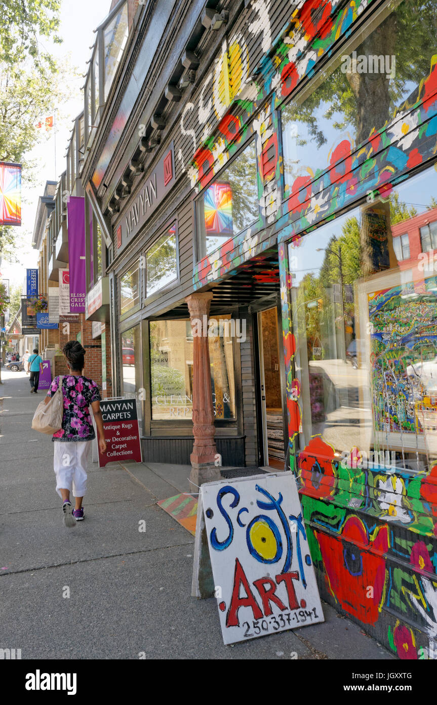 Woman walking past a colorful painted facade of an art store on gallery ...