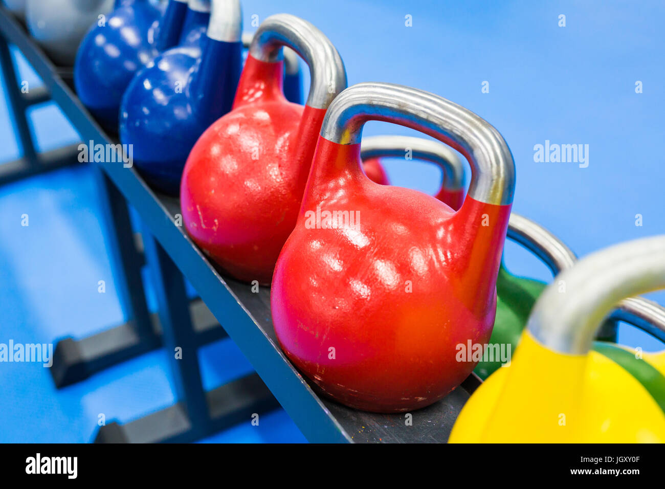 colorful kettlebells in a row in a gym - focus on the front kettlebell ...