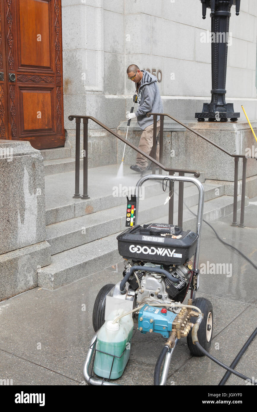 Building maintenance man cleaning building entrance with pressure ...