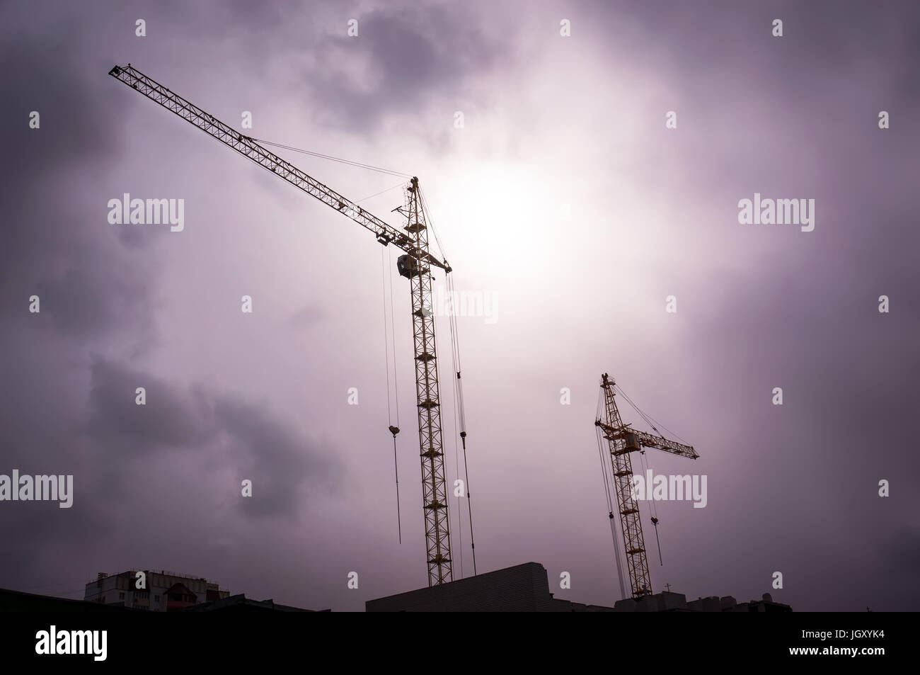 two high tower crane and building under construction against the dark ...