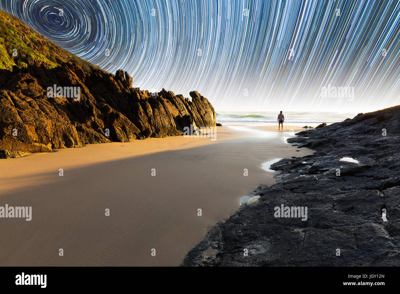 A man standing on a beautiful, isolated beach in Australia underneath a ...
