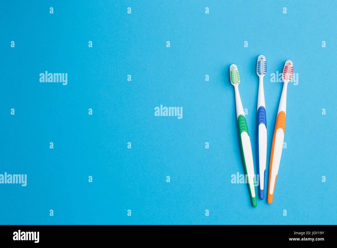 Three multi-colored toothbrushes on empty blue background Stock Photo ...