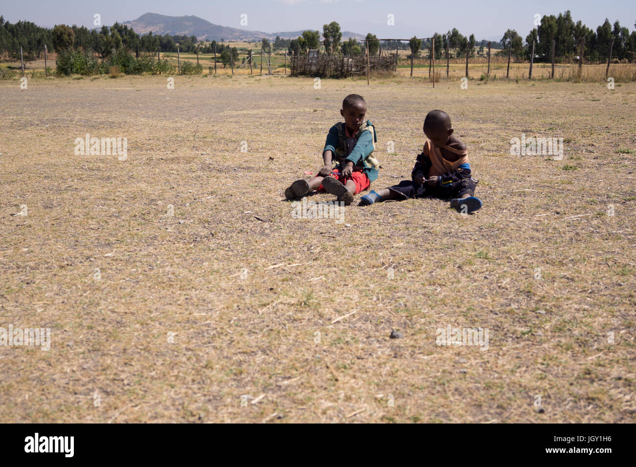 two black children sitting on a dry ground in ethiopia Stock Photo - Alamy