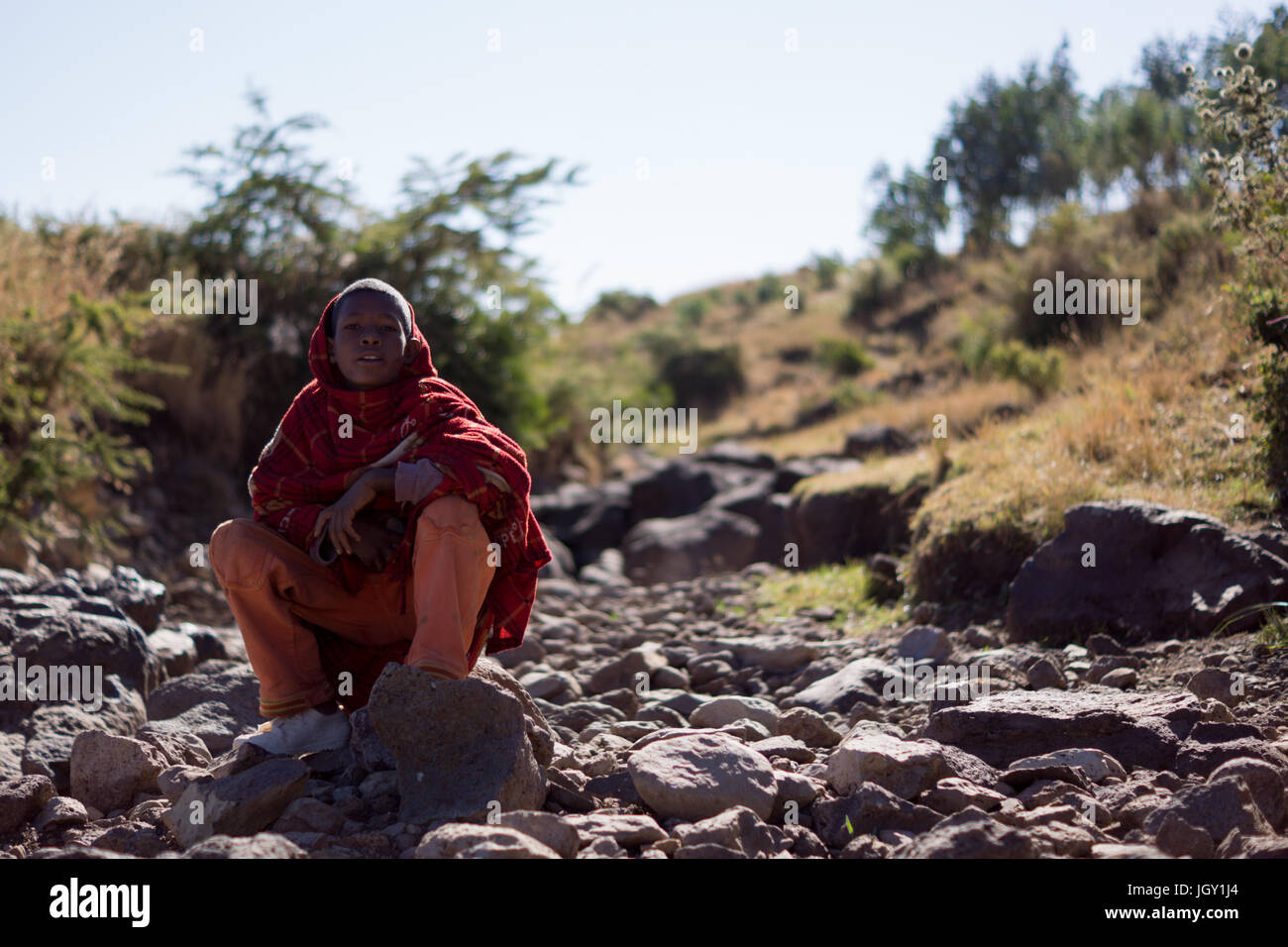young black boy sitting on rocks of empty stream Stock Photo - Alamy