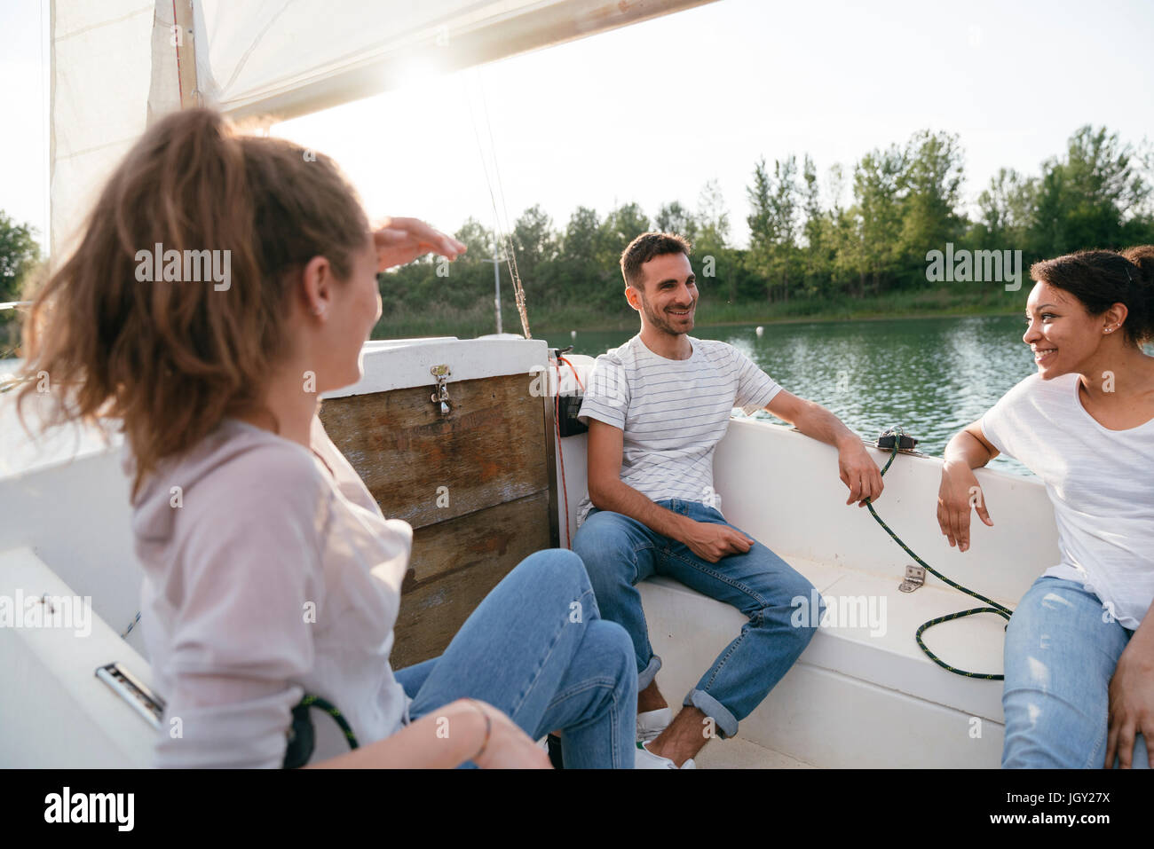Three friends relaxing on sailing boat on lake Stock Photo - Alamy