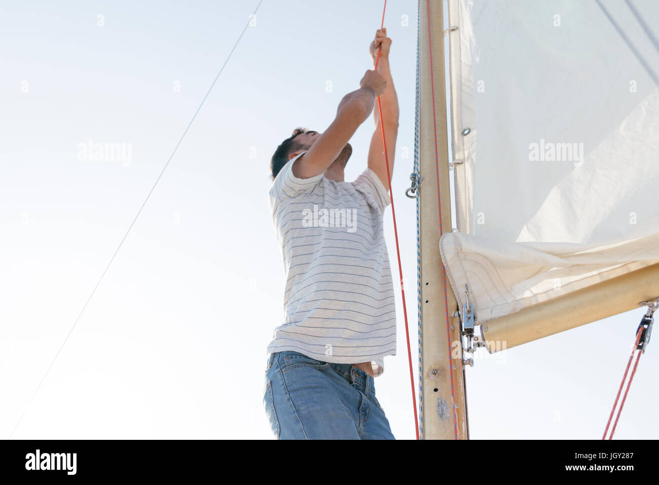 Man on sailing boat, hoisting sail Stock Photo - Alamy