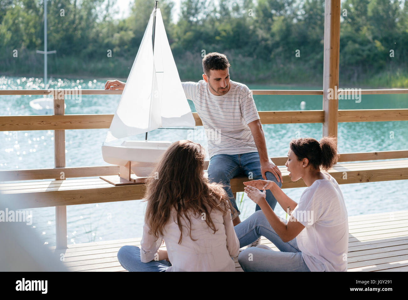 Man talking through sailing boat parts, to two women at nautical club ...
