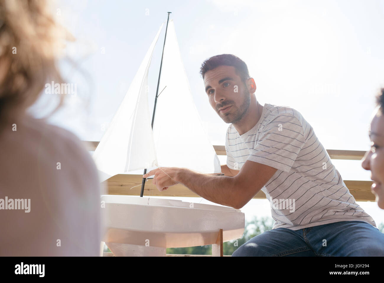 Man talking through sailing boat parts, to two women at nautical club ...