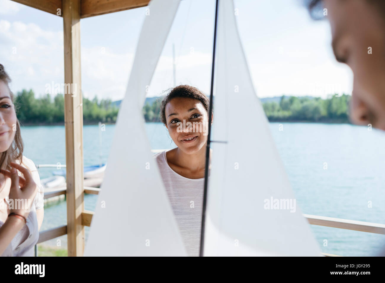 Man talking through sailing boat parts, to two women at nautical club ...