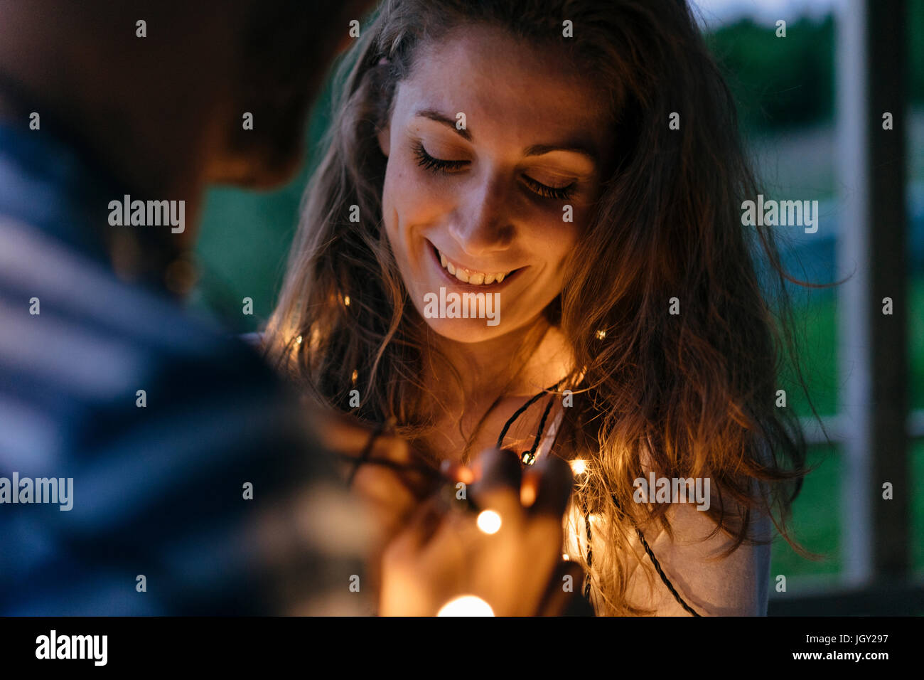 Man and woman standing face to face, illuminated fairy lights wrapped ...