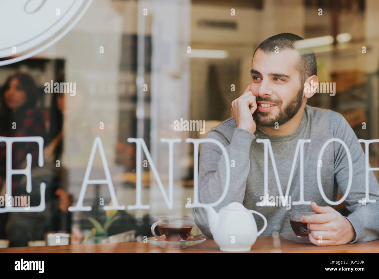 Young man sitting in cafe, view through window Stock Photo - Alamy