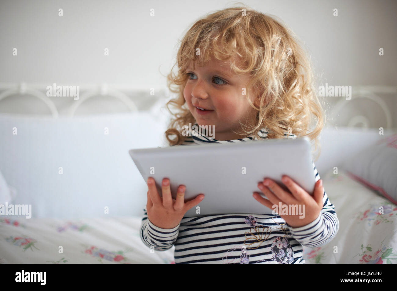 Little girl using digital tablet on bed Stock Photo - Alamy