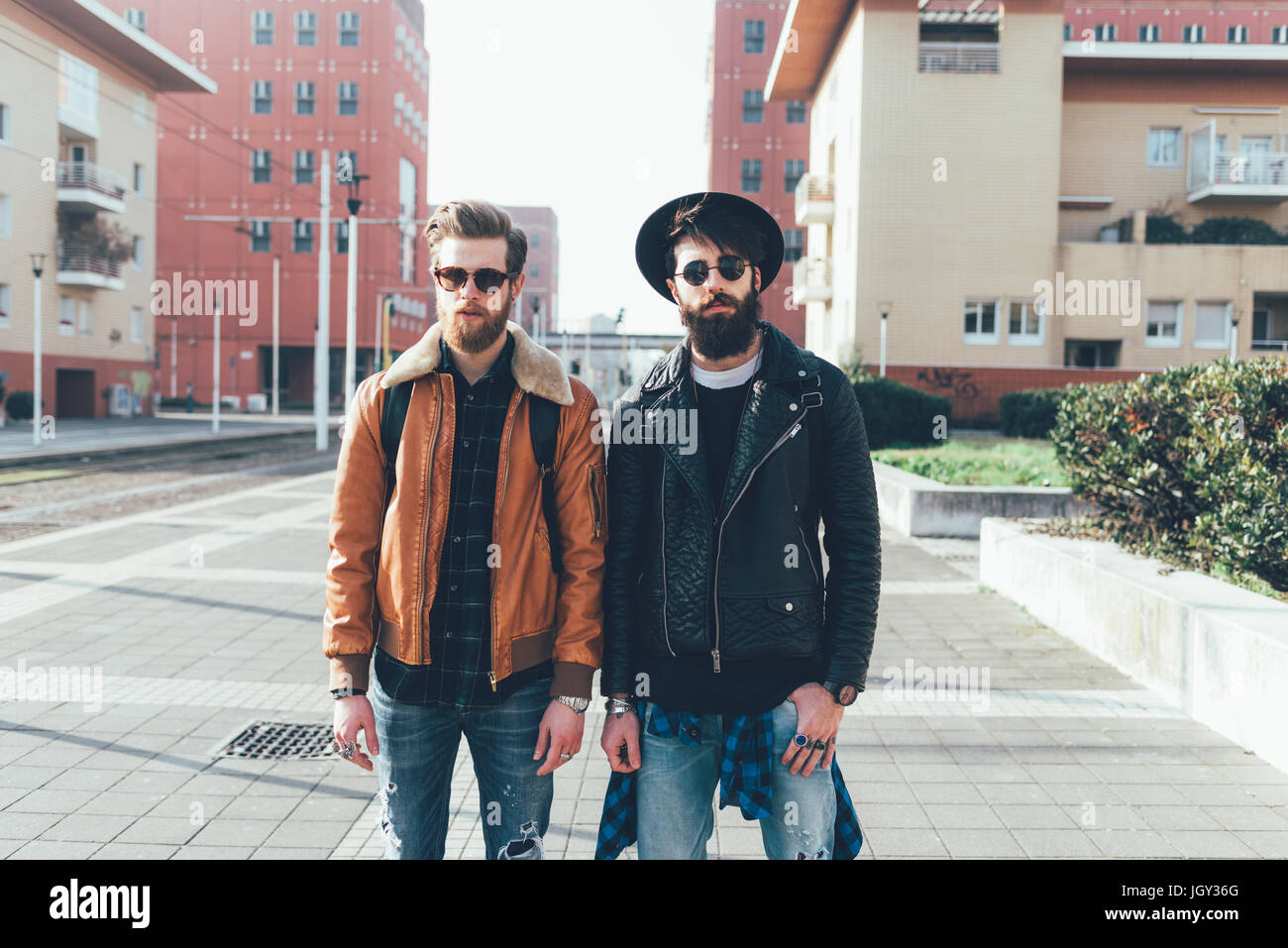 Portrait of two young male hipster friends standing in city housing ...