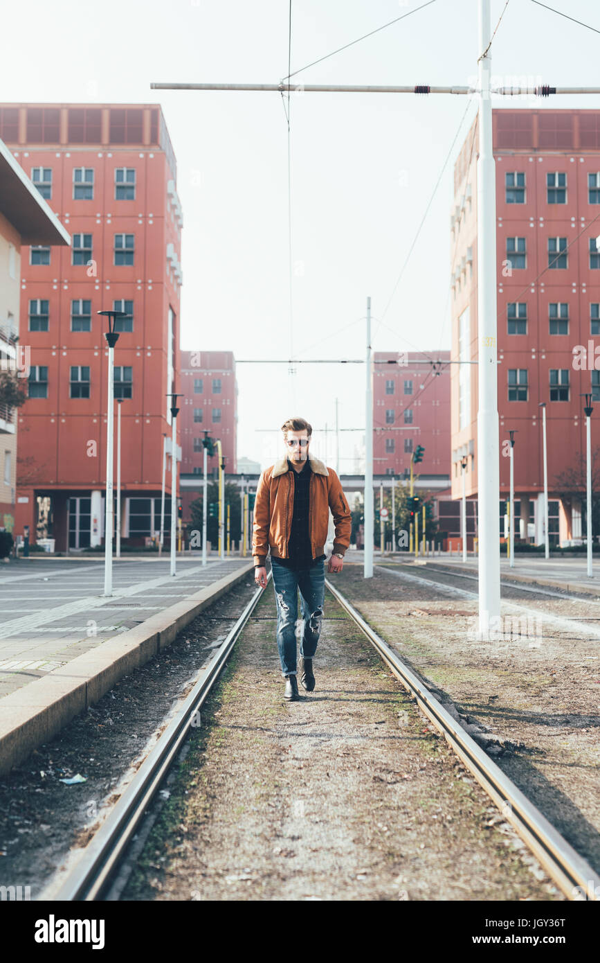 Young caucasian shirtless man wearing swimwear walking on a beach on a ...