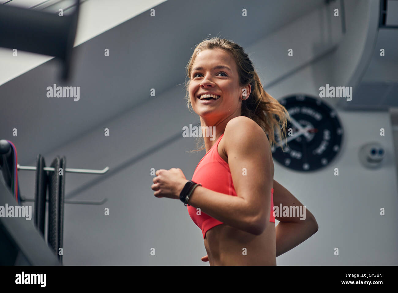 Young woman training, running on gym treadmill looking over her ...