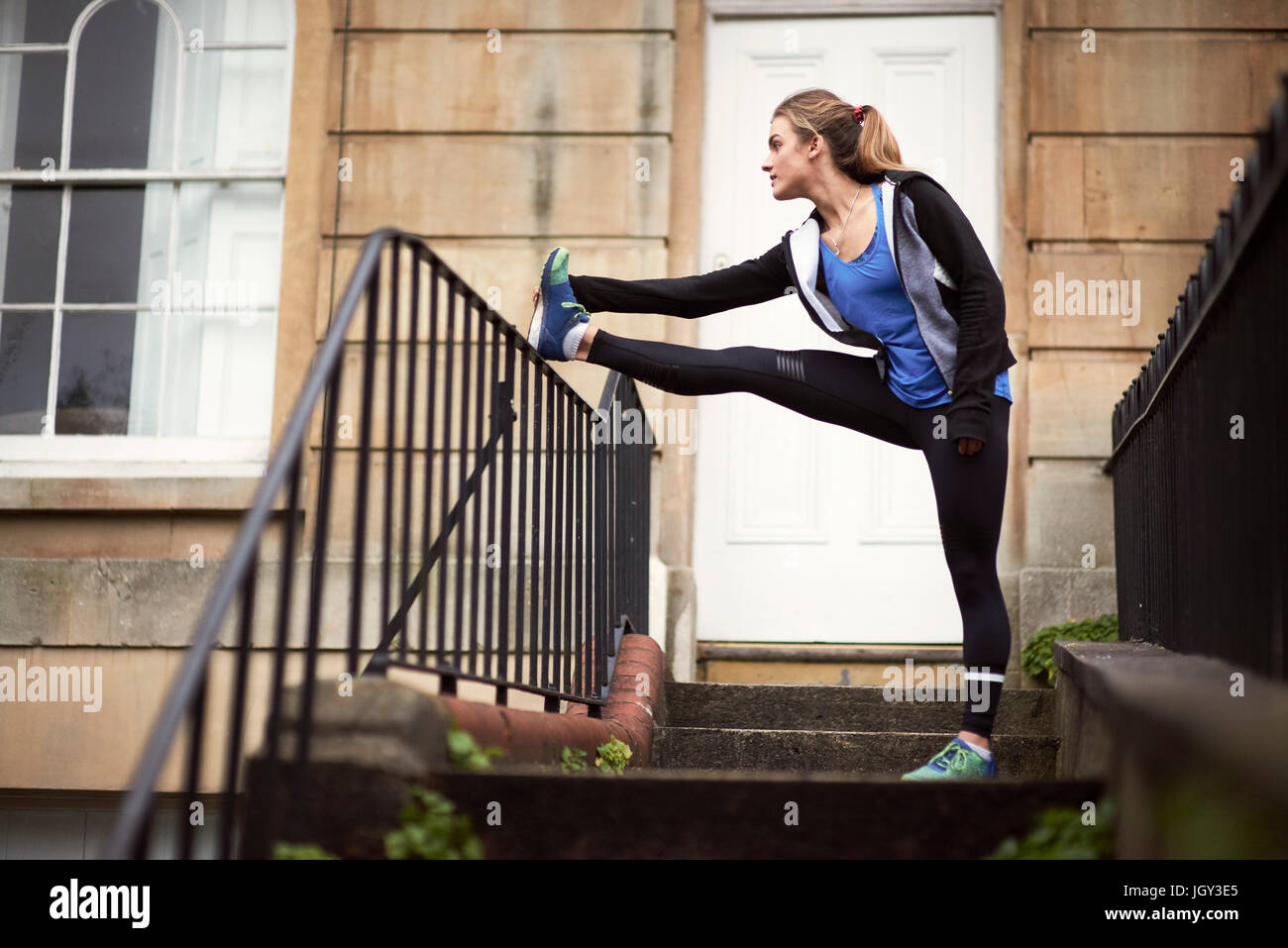 Young female runner outside front door touching toes Stock Photo - Alamy