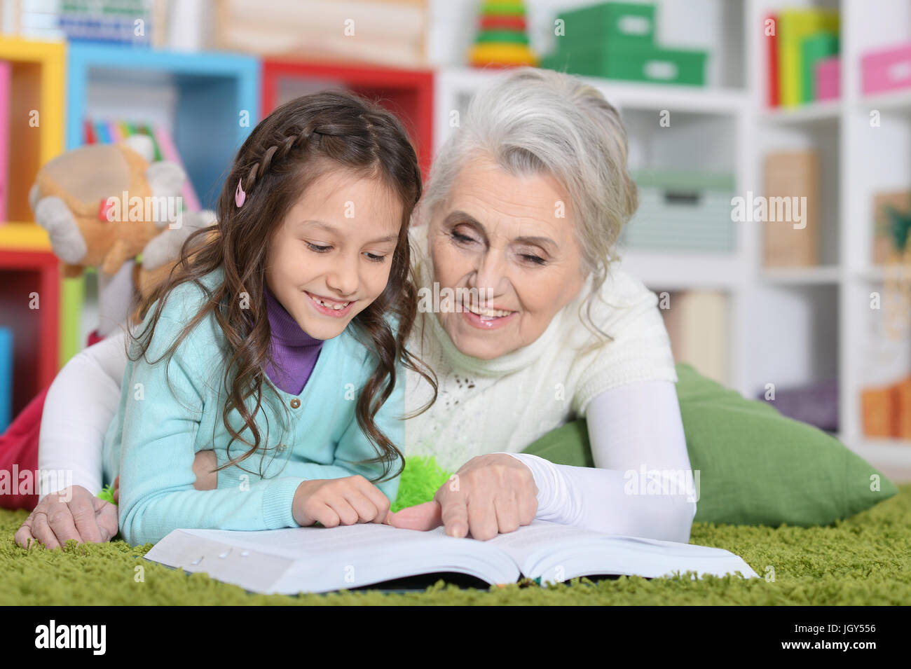 Grandmother reading book with her granddaughter Stock Photo - Alamy
